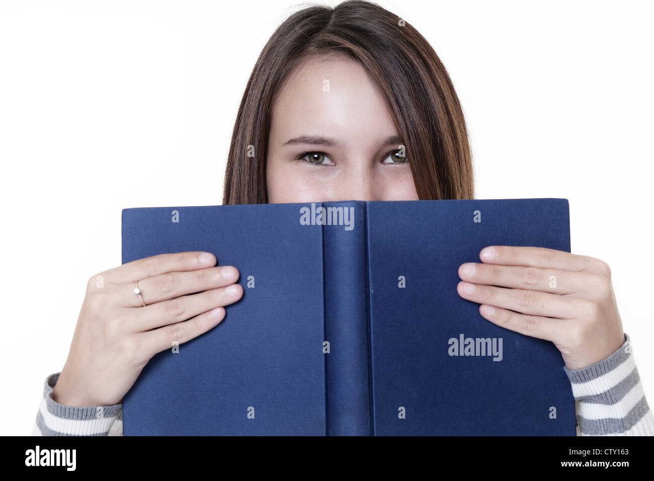 young woman peering over a hard back book Stock Photo - Alamy