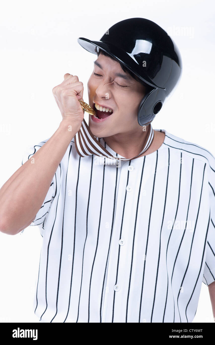 A baseball player biting gold medal Stock Photo - Alamy