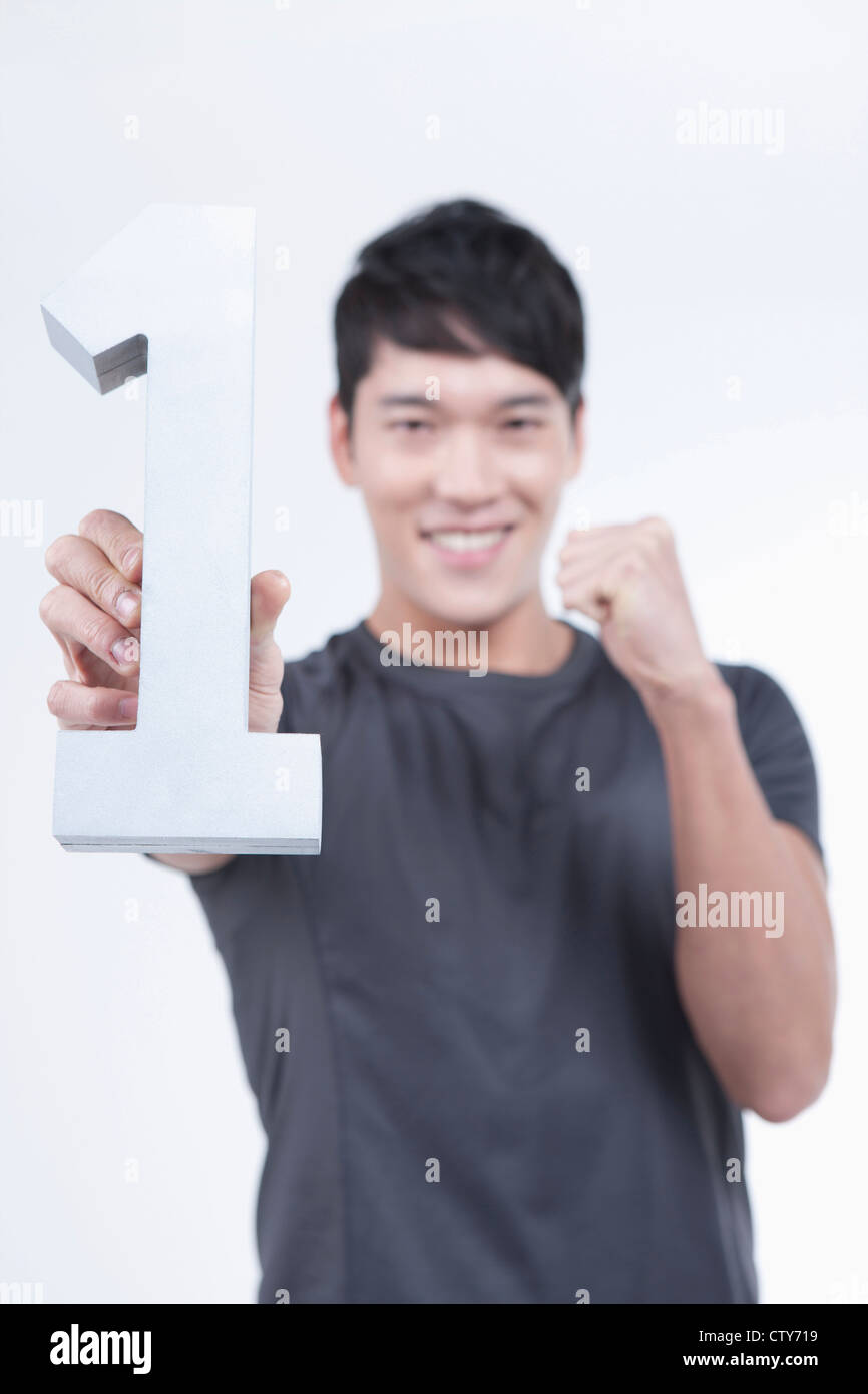 A cheerful man holding the number one Stock Photo - Alamy