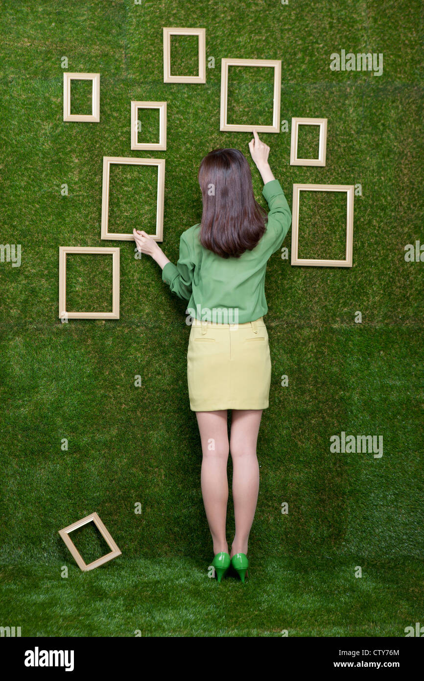 A woman pointing at the frame on the green wall Stock Photo - Alamy