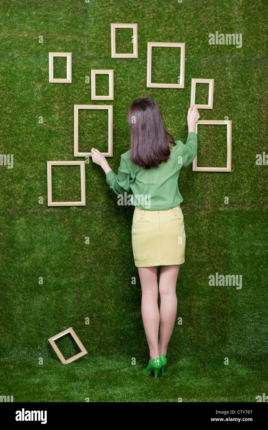 A woman looking at the frames on the green wall Stock Photo - Alamy