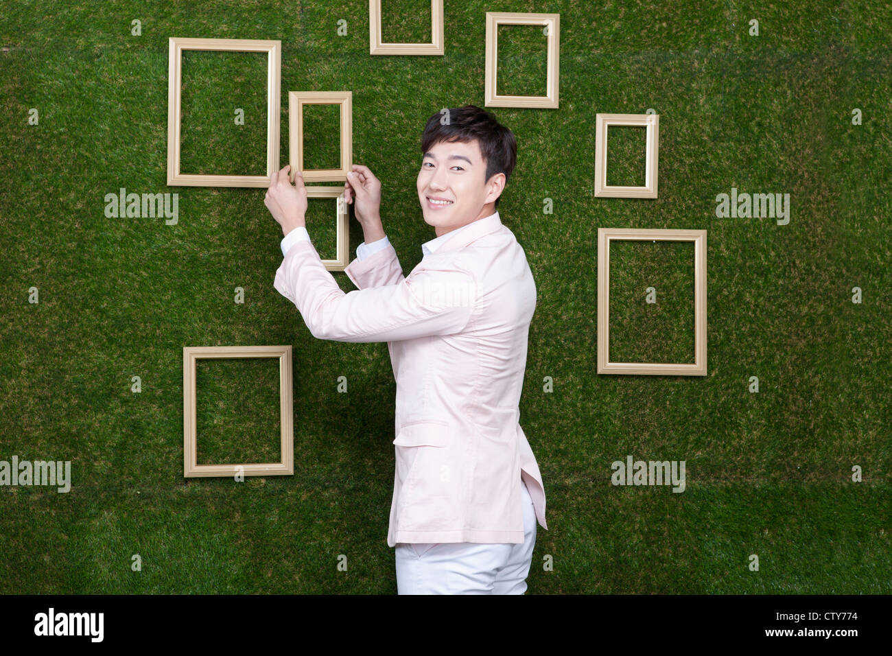 A man holding a frame from the green wall Stock Photo - Alamy