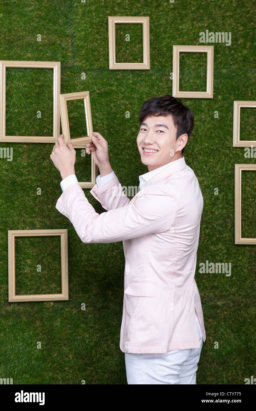 A man holding a frame from the green wall Stock Photo - Alamy