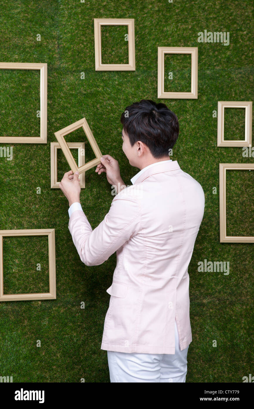 A man holding a frame from the green wall Stock Photo - Alamy