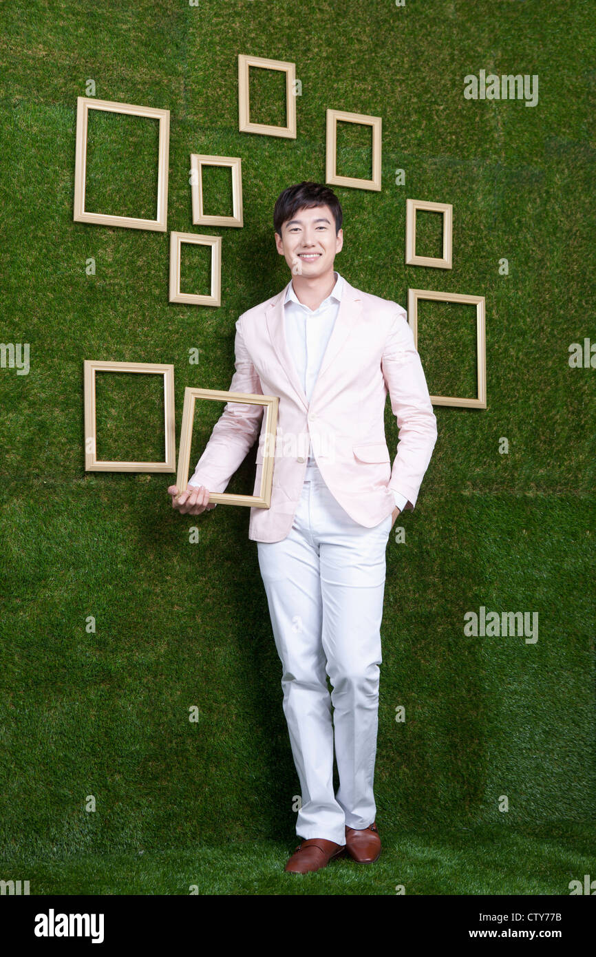 A man holding a frame from the green wall Stock Photo - Alamy
