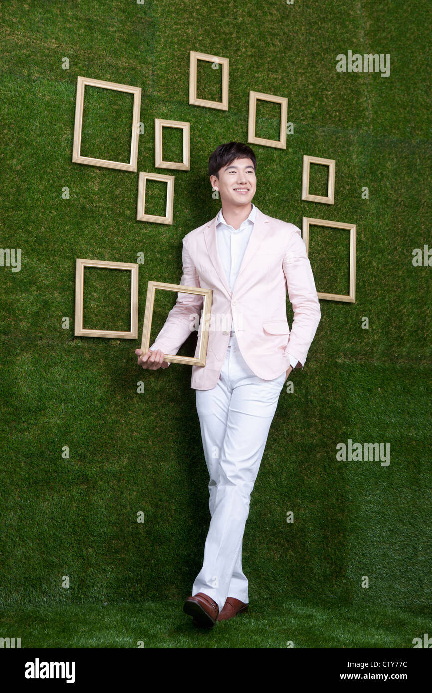 A man holding a frame from the green wall Stock Photo - Alamy
