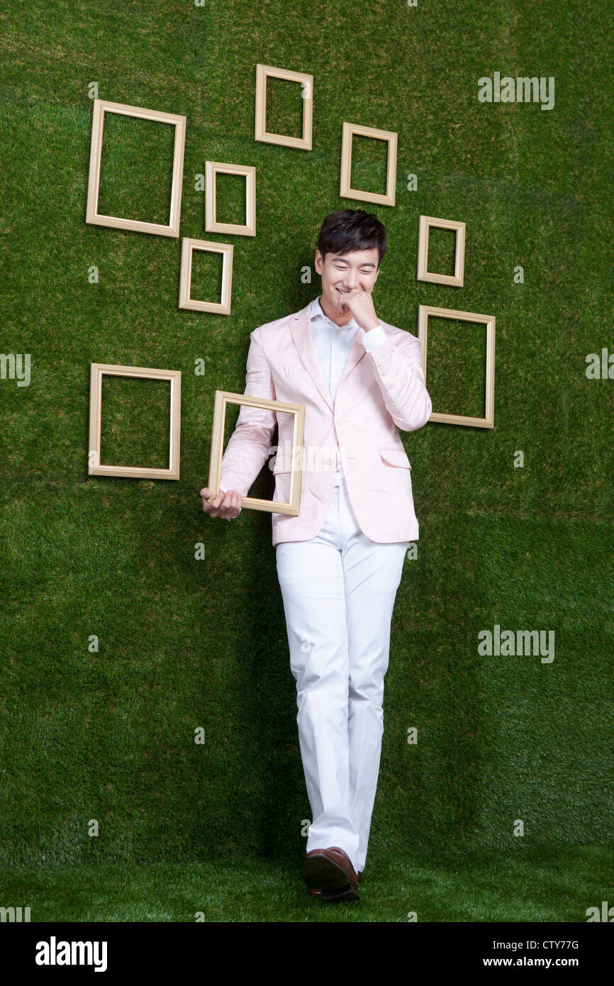 A man holding a frame from the green wall Stock Photo - Alamy