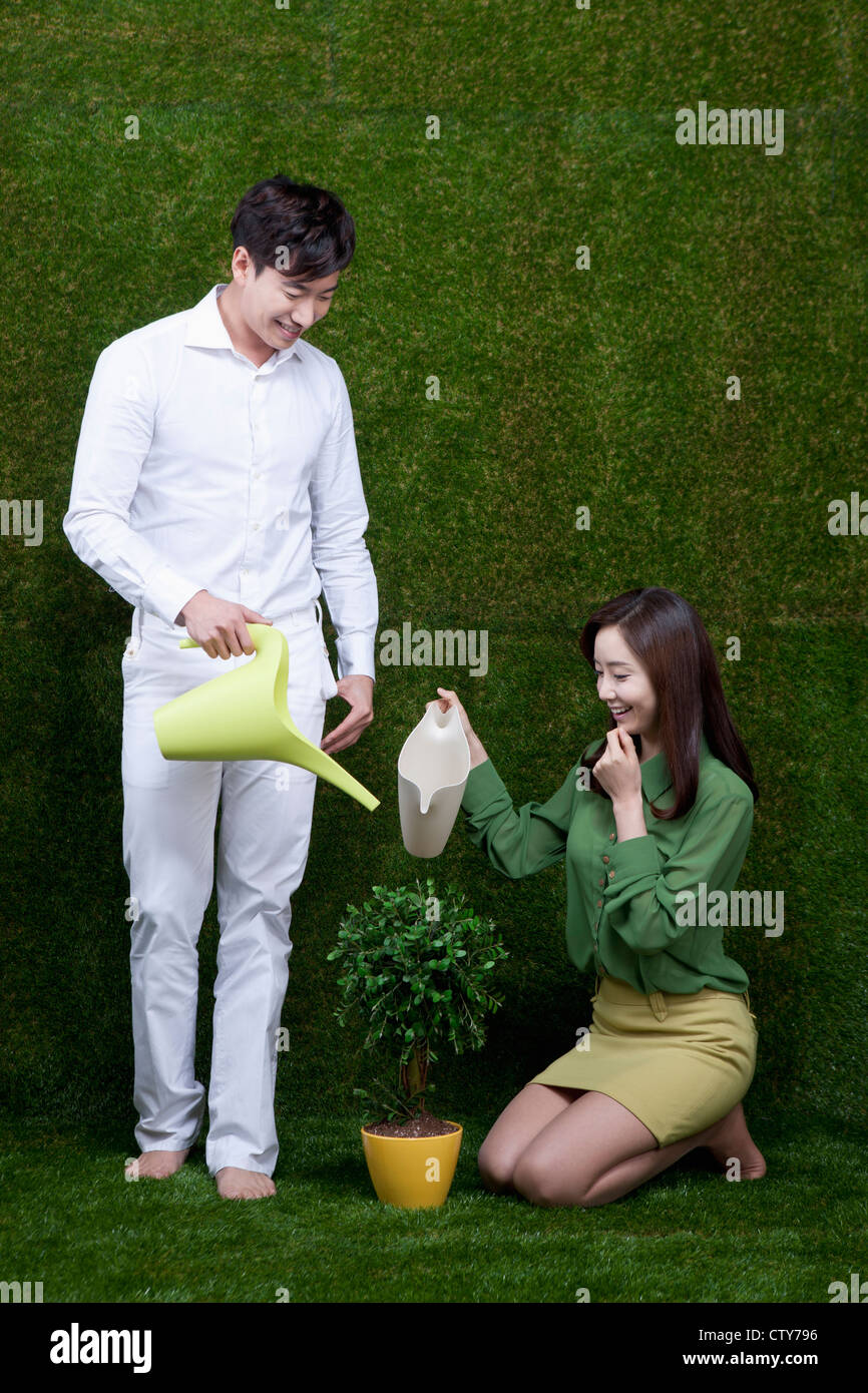 A man and woman watering the tree Stock Photo - Alamy
