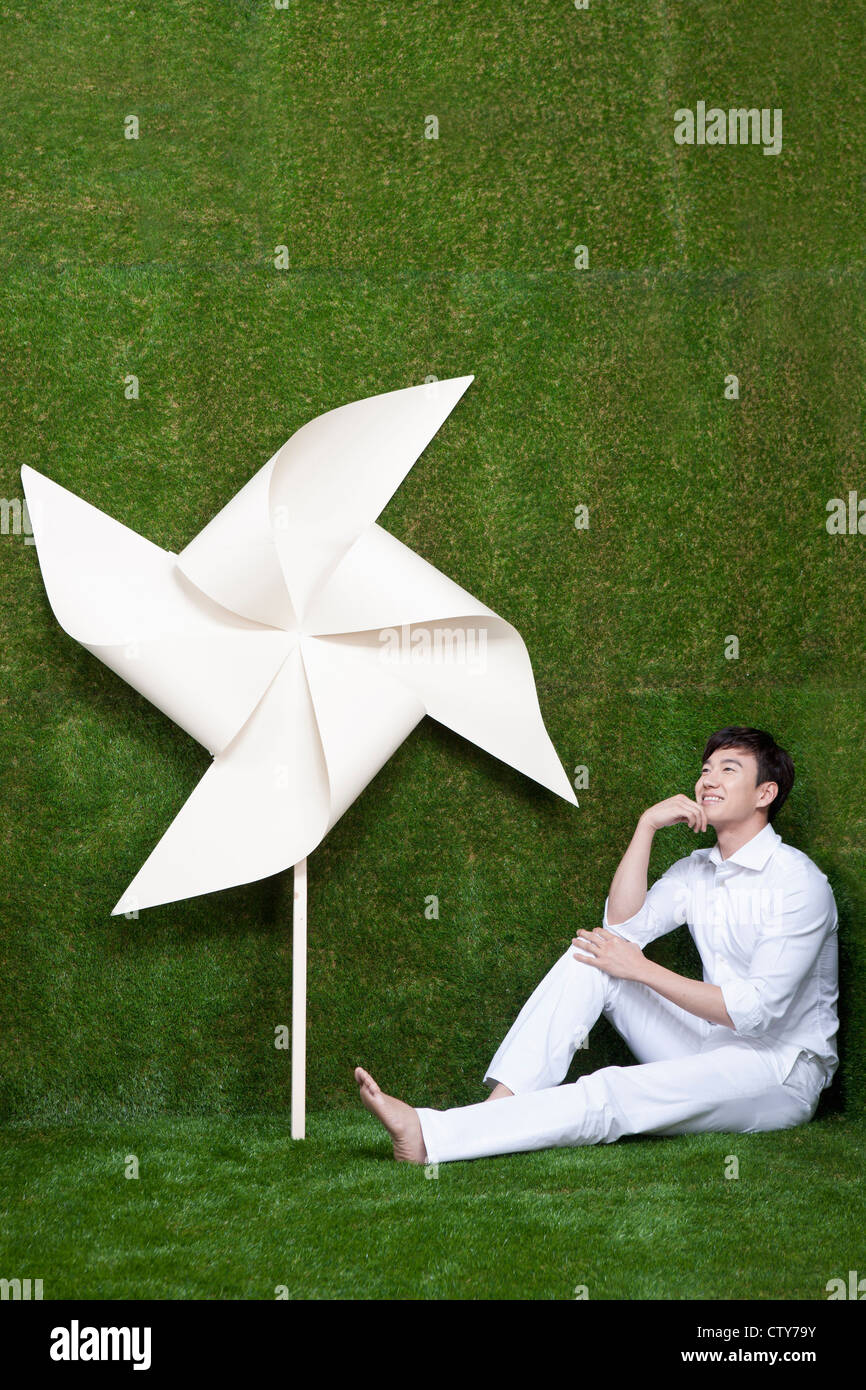 A man sitting with a white pinwheel Stock Photo - Alamy