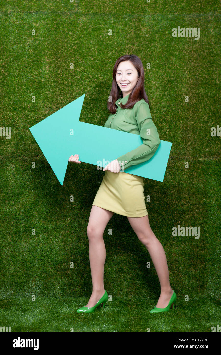 A woman standing with a green arrow Stock Photo - Alamy