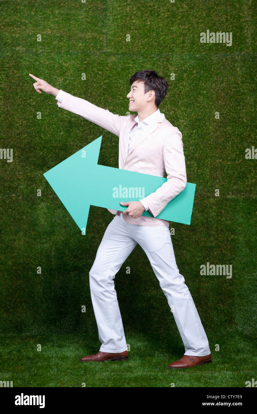 A man pointing at left side with a green arrow Stock Photo - Alamy