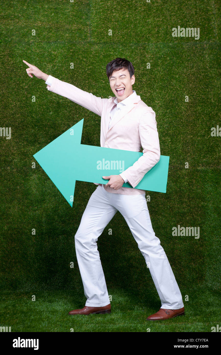 A man pointing at left side with a green arrow Stock Photo - Alamy