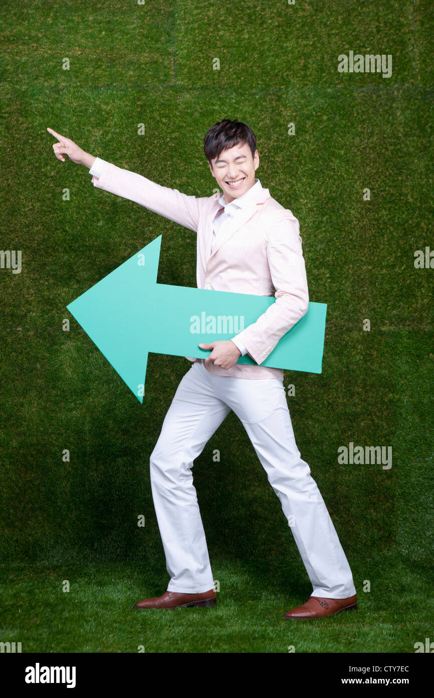 A man pointing at left side with a green arrow Stock Photo - Alamy