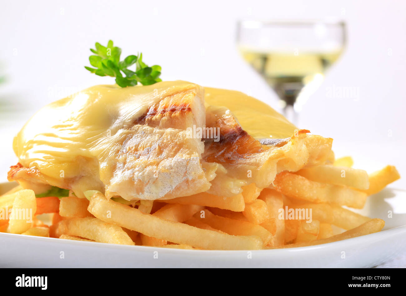 Cheese topped fish fillets served with French fries Stock Photo - Alamy