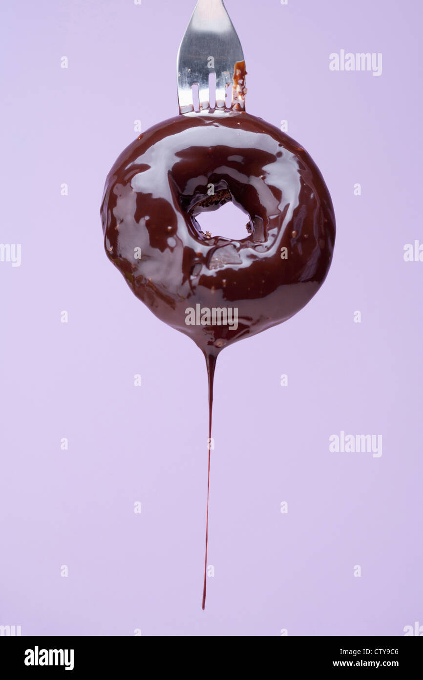 Donut dripping chocolate with fork Stock Photo - Alamy