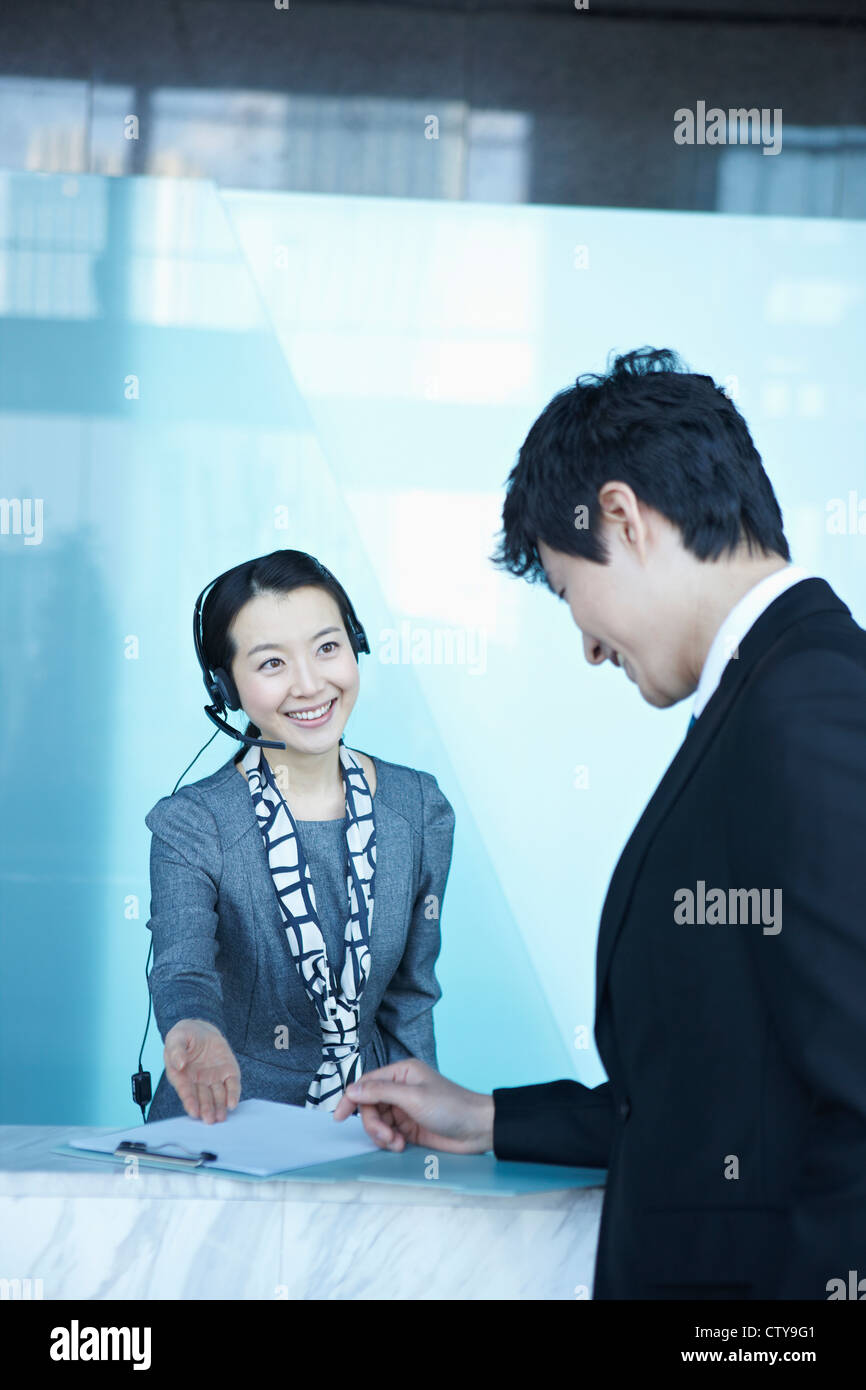 A receptionist guiding a businessman Stock Photo - Alamy