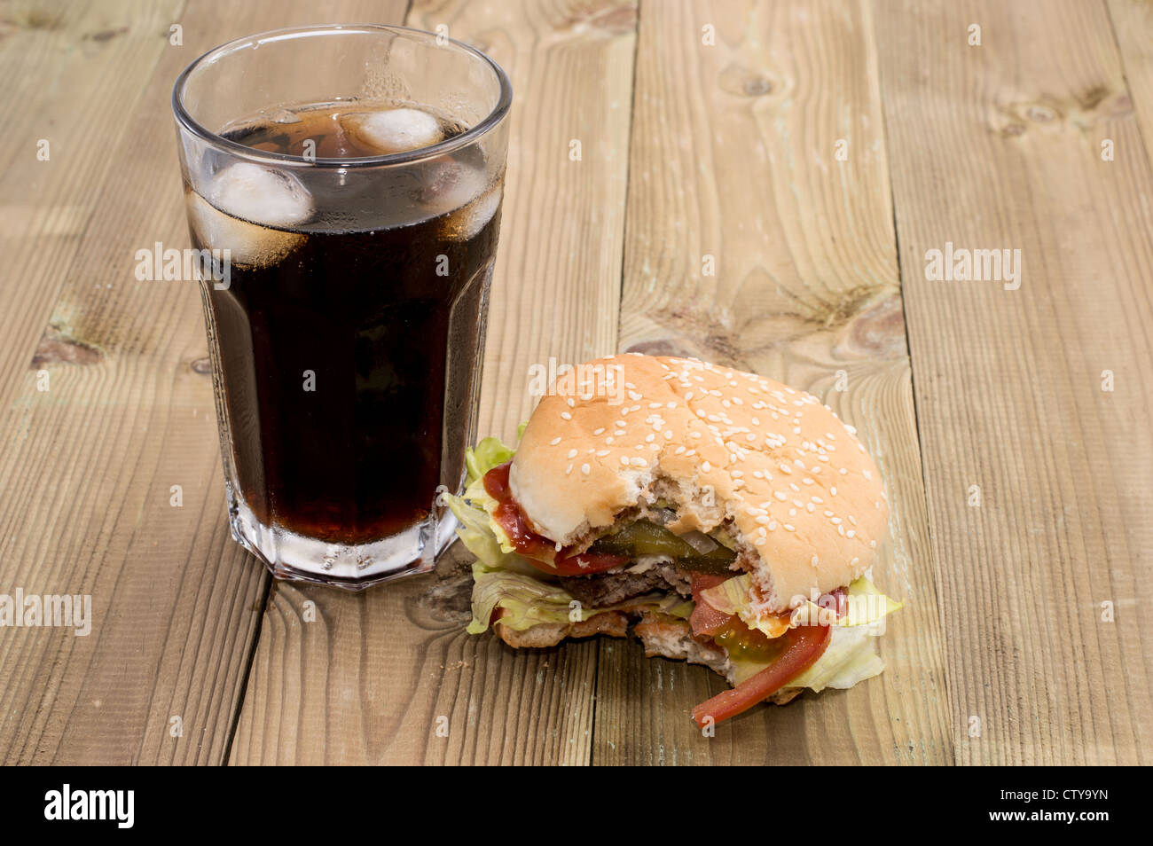 Bitten Off Burger with Softdrink on wooden background Stock Photo - Alamy