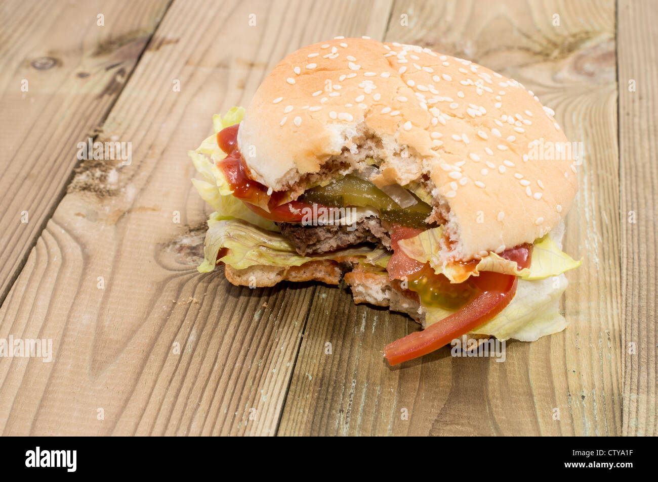 Bitten Off Burger on wooden background Stock Photo - Alamy