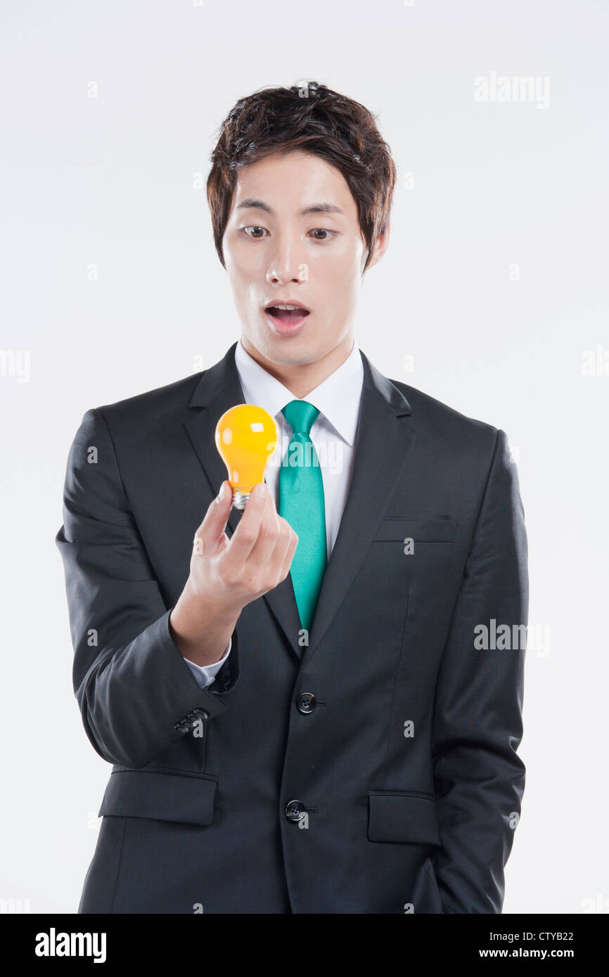A man holding a yellow light bulb Stock Photo - Alamy