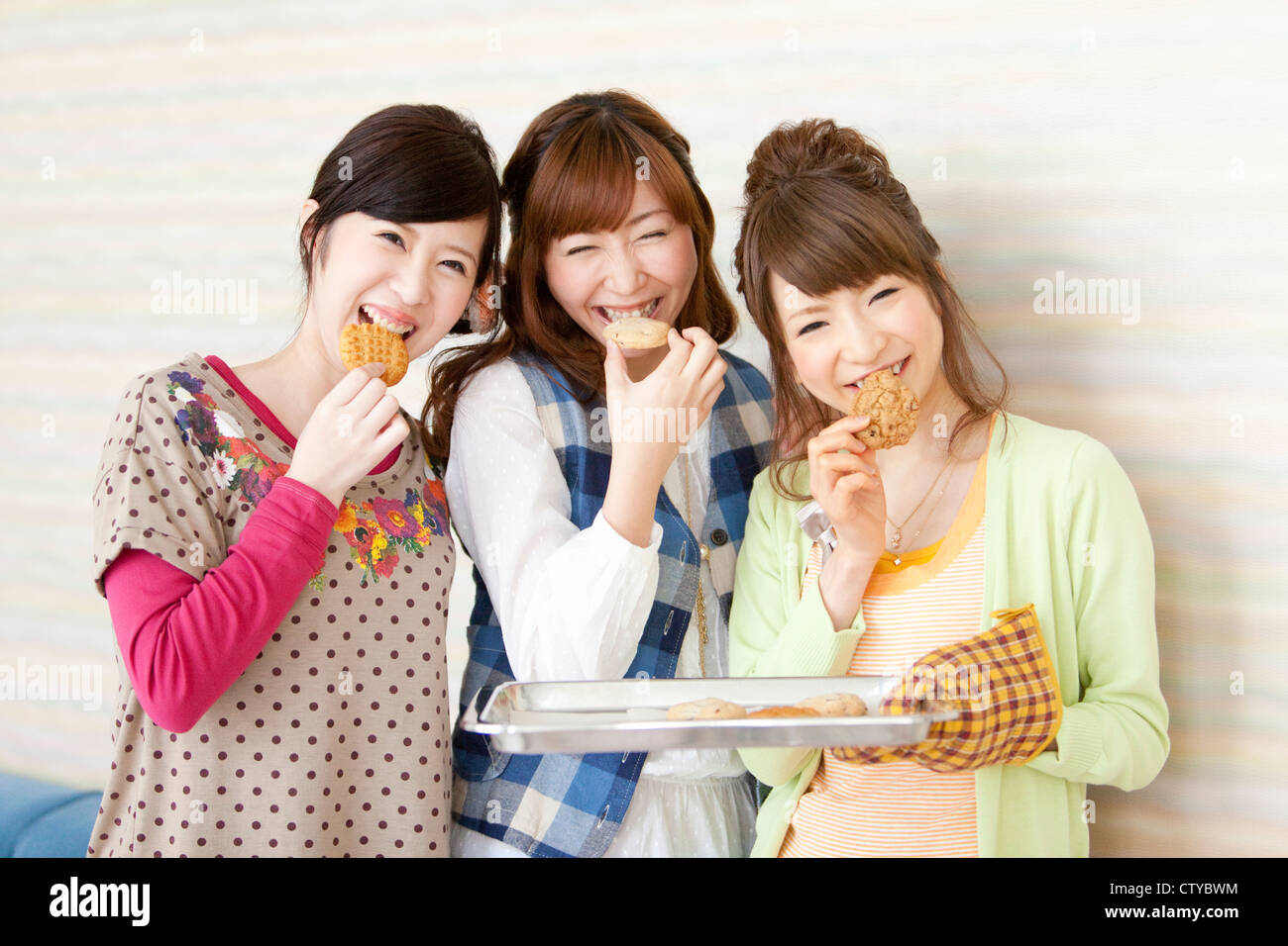 Three women eating cookies Stock Photo - Alamy