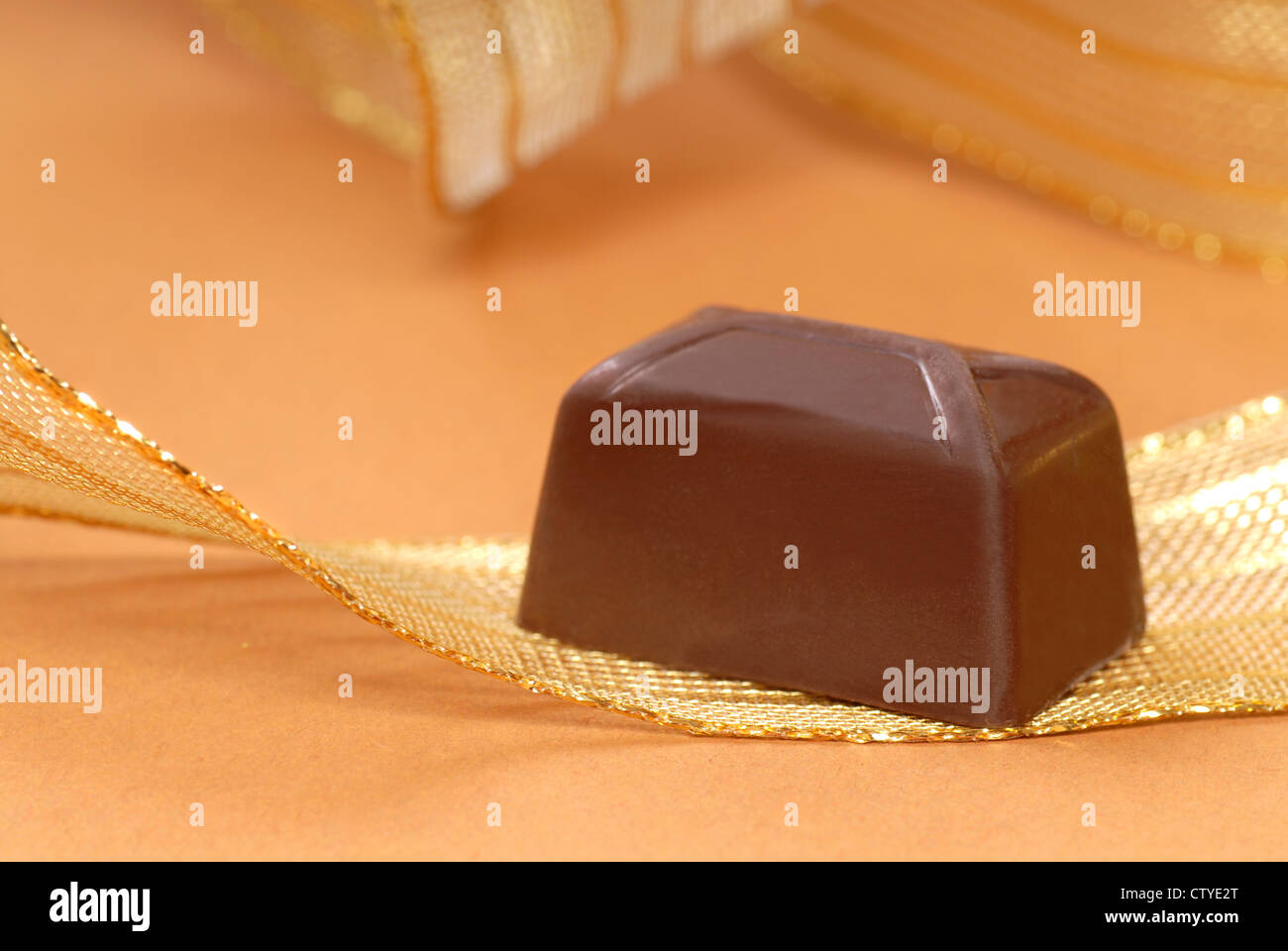 Delicious dark chocolate bonbon resting on a gold ribbon Stock Photo ...