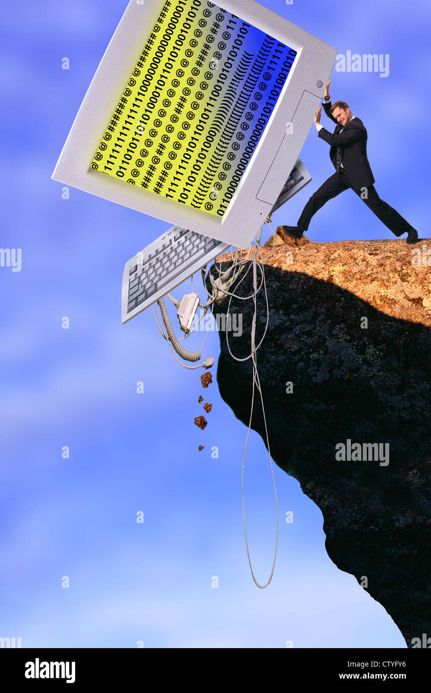 Businessman pushing computer off cliff Stock Photo - Alamy