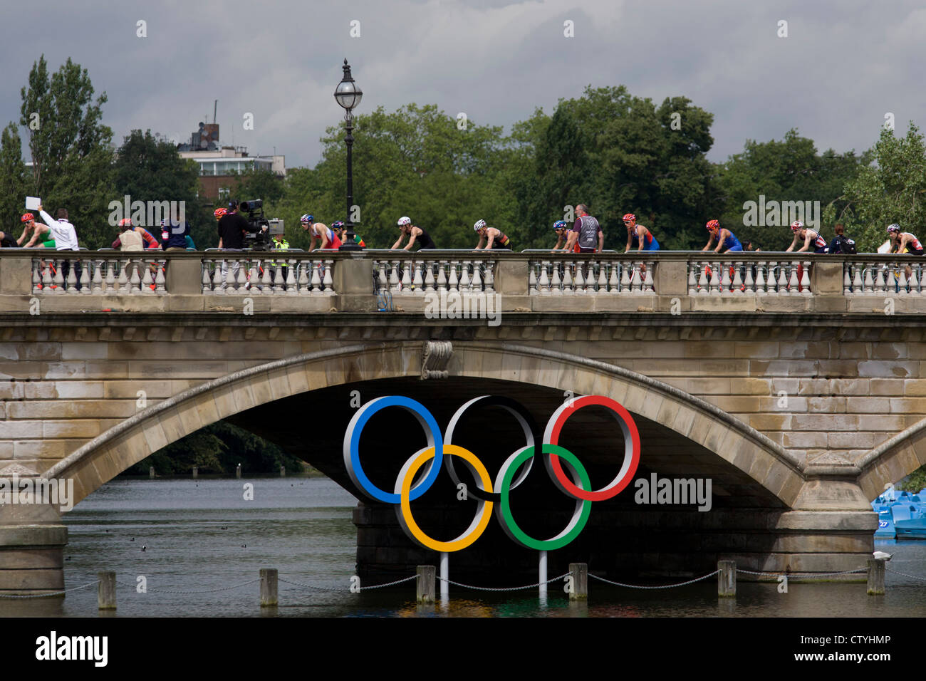 Triathletes cycle over Serpentine Bridge in London's Hyde Park for the ...