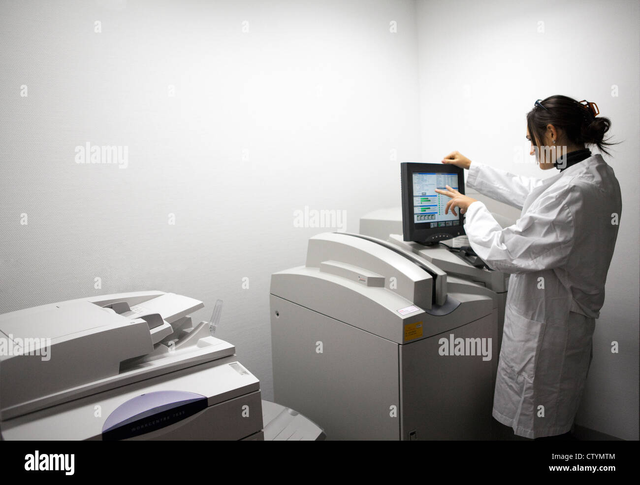 Young female doctor operates the printing equipment in radiology ...