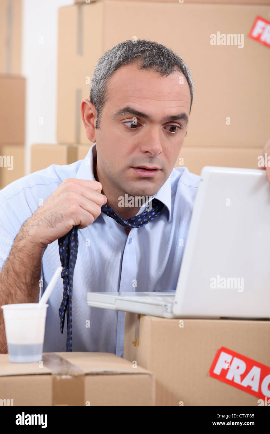 Panicking man using a laptop surrounded by boxes Stock Photo - Alamy