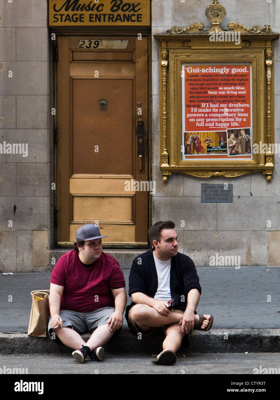 Two men sit on the sidewalk curb at stage entrance to the Music Box ...