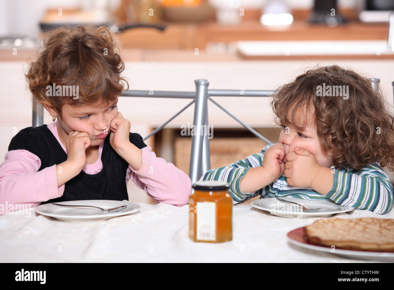 Grumpy children at a table with pancakes Stock Photo - Alamy