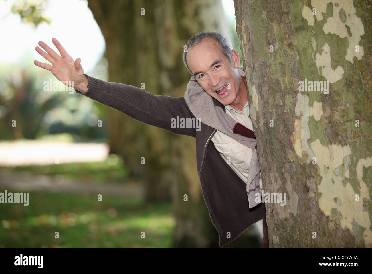 Man jumping out from behind tree Stock Photo - Alamy