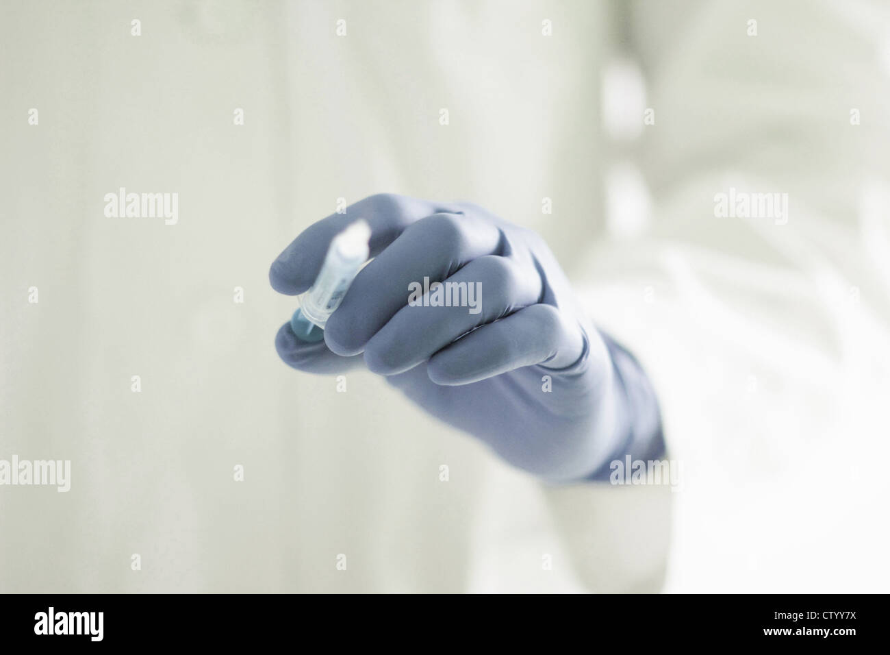 Gloved hand holding syringe Stock Photo - Alamy
