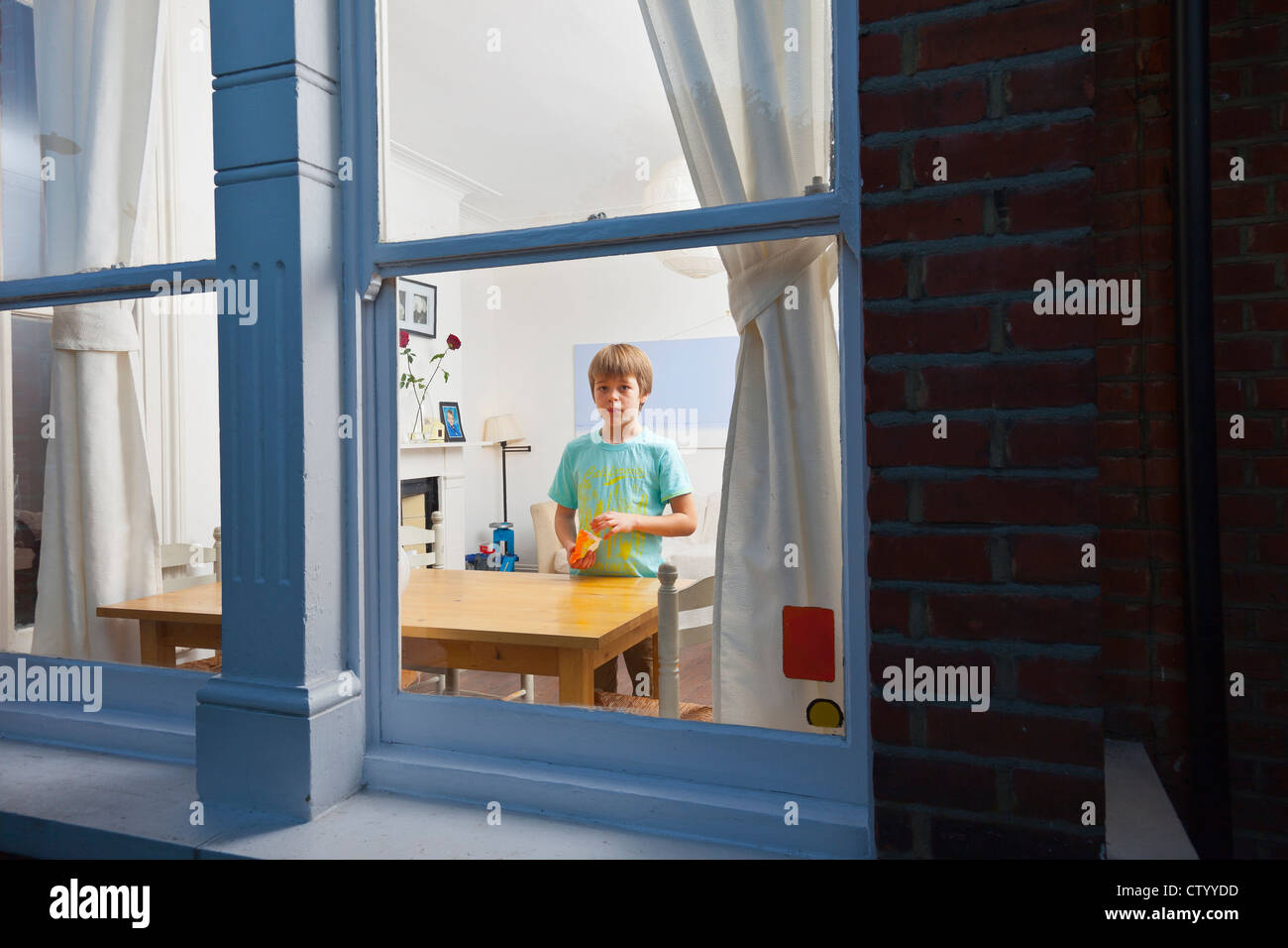 Boy in living room viewed through window Stock Photo - Alamy