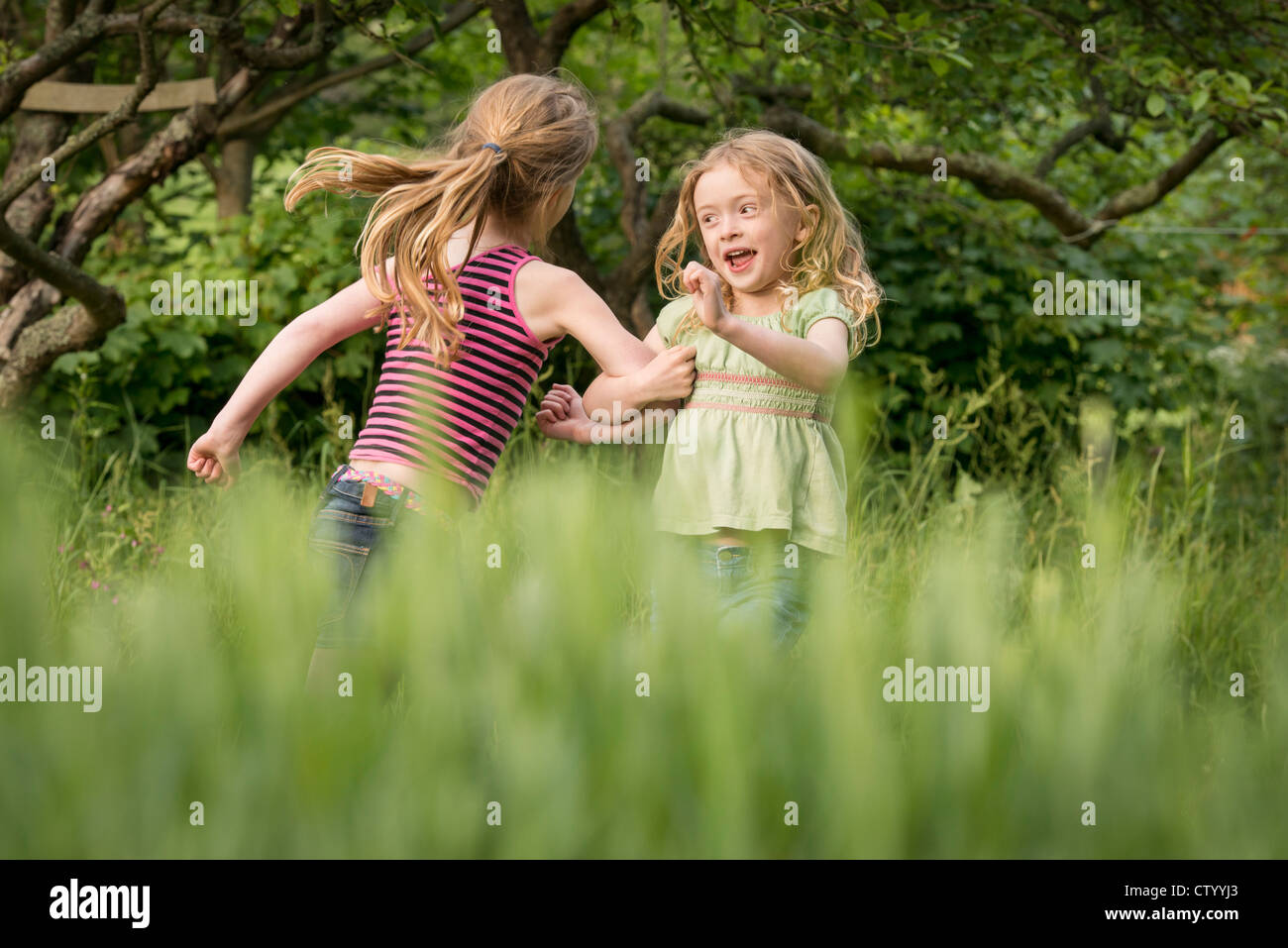 Girls running together in tall grass Stock Photo - Alamy