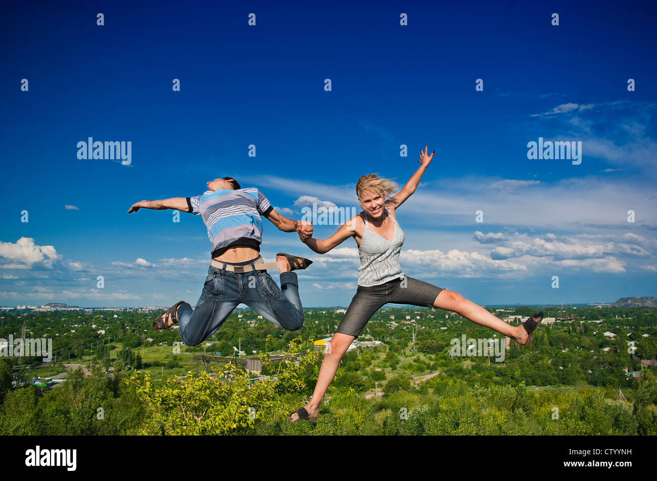 Boy and girl jumping against a background of beautiful sky Stock Photo ...
