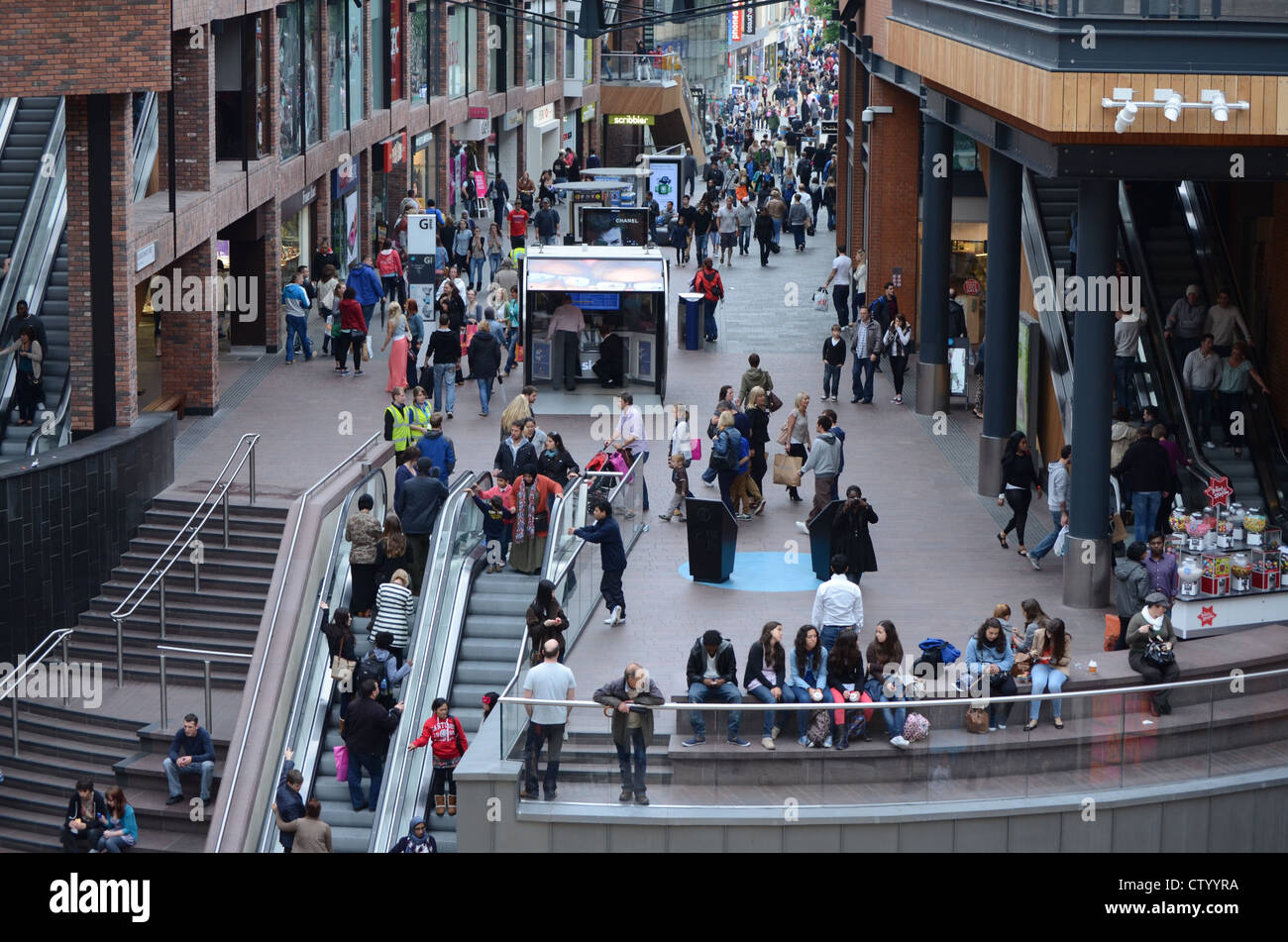 Busy shopping centre with people on escalators and in the distance ...
