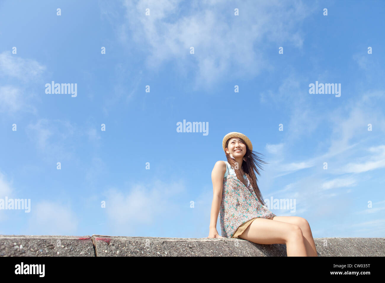 Woman sitting on retaining wall Stock Photo - Alamy
