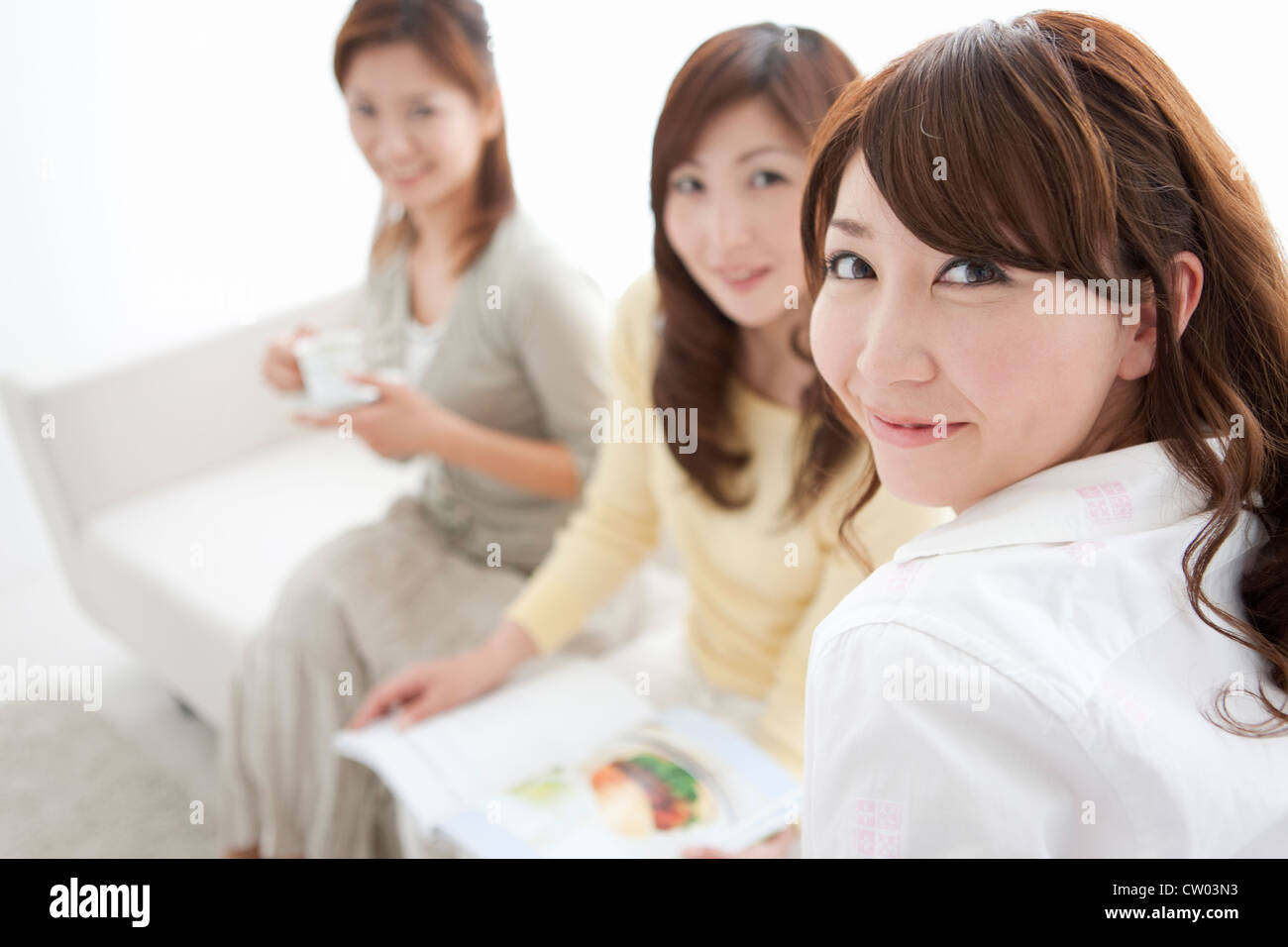 Three women sitting on sofa looking at camera Stock Photo - Alamy