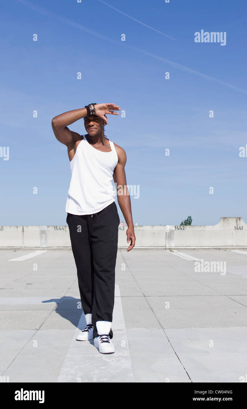 Man shielding his eyes on urban rooftop Stock Photo - Alamy