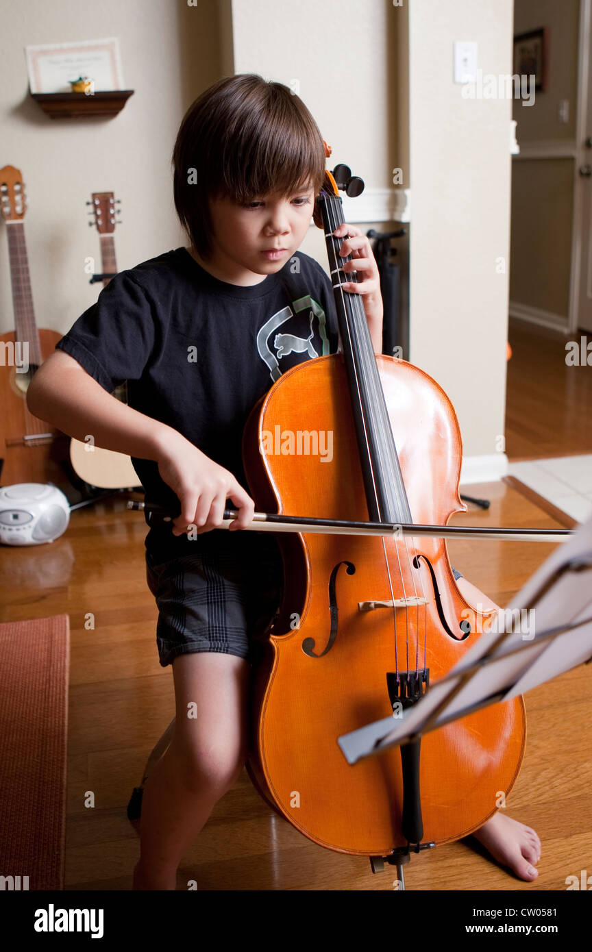 Japanese-American 8 year old boy practices music lessons playing cello ...