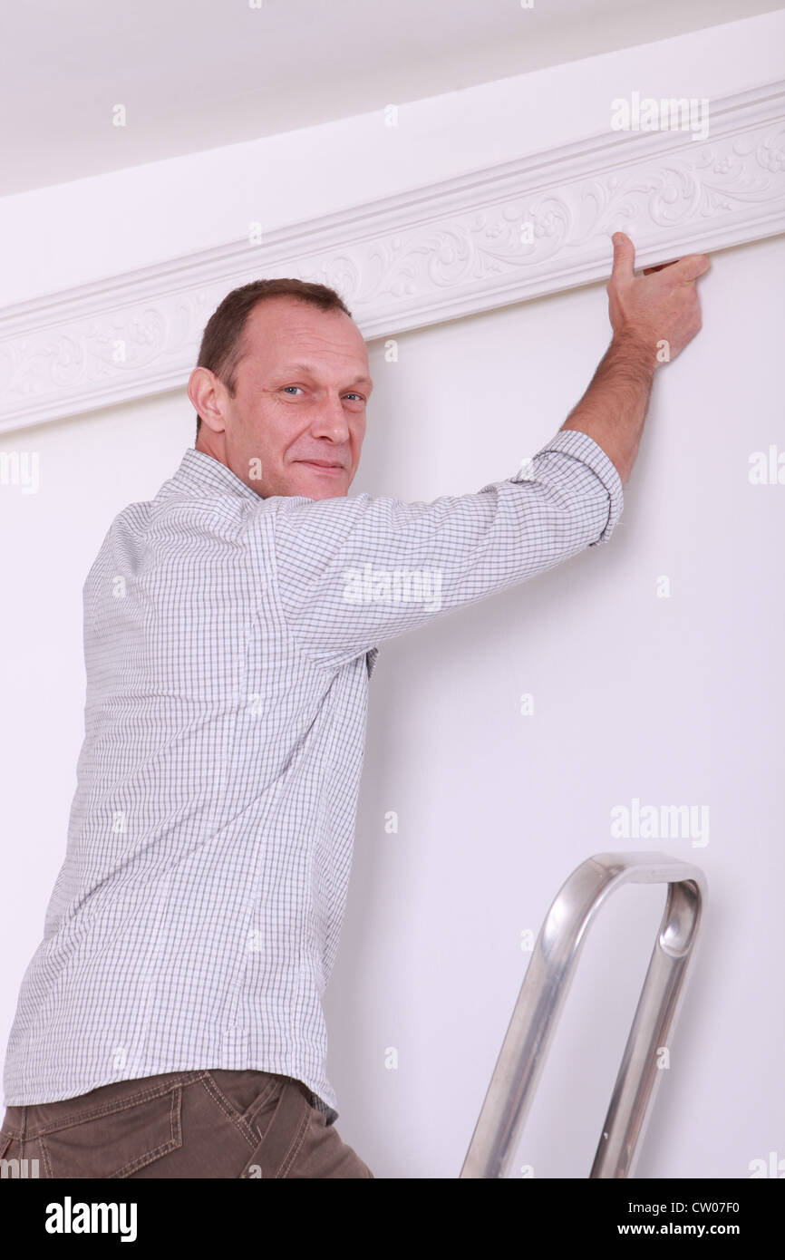 Smiling man fixing coving to a ceiling Stock Photo - Alamy