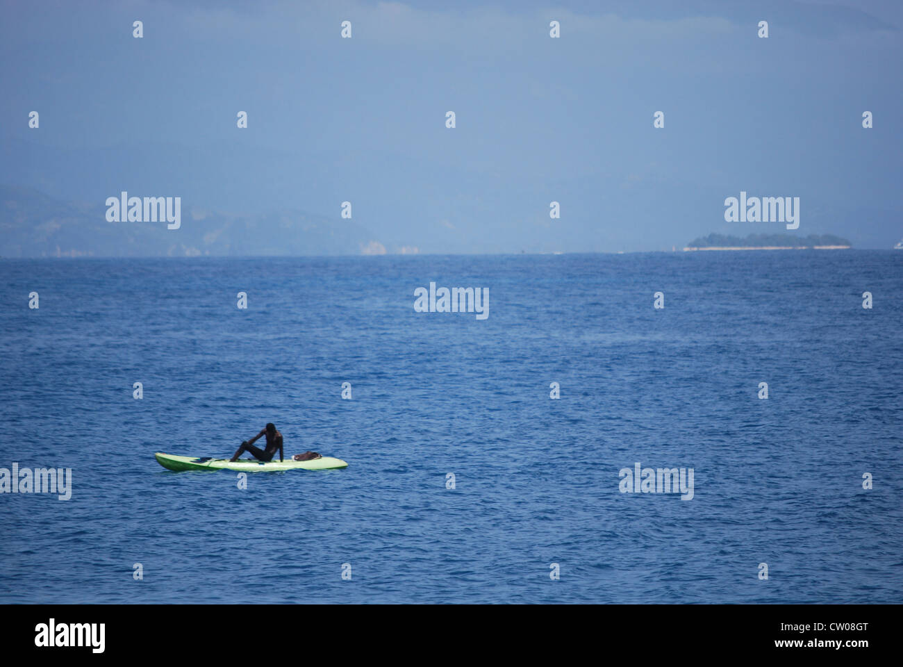 This photograph was taken in Jamaica of a man sunbathing on a surfboard ...