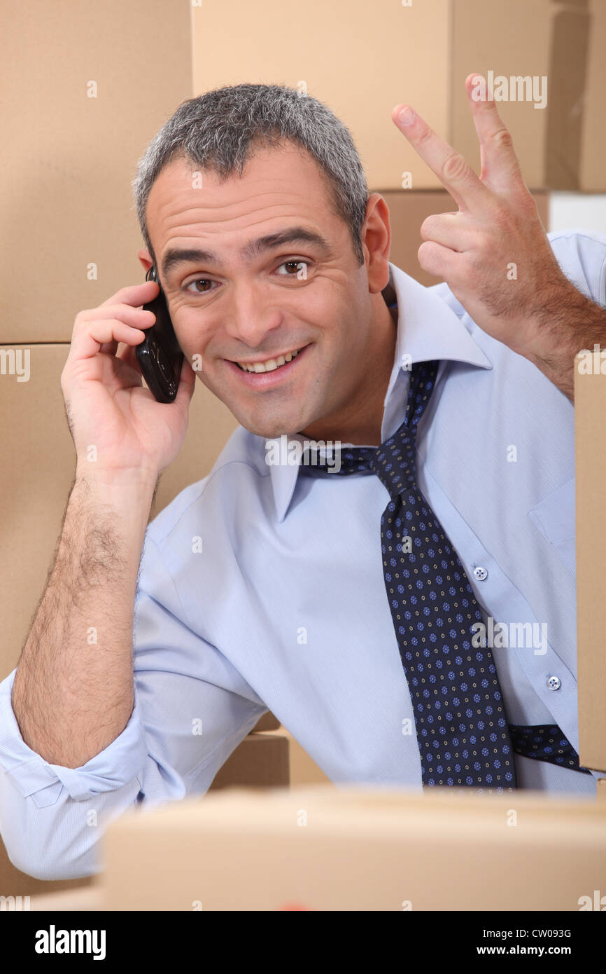 a business man calling someone in a room full of cardboard boxes Stock ...