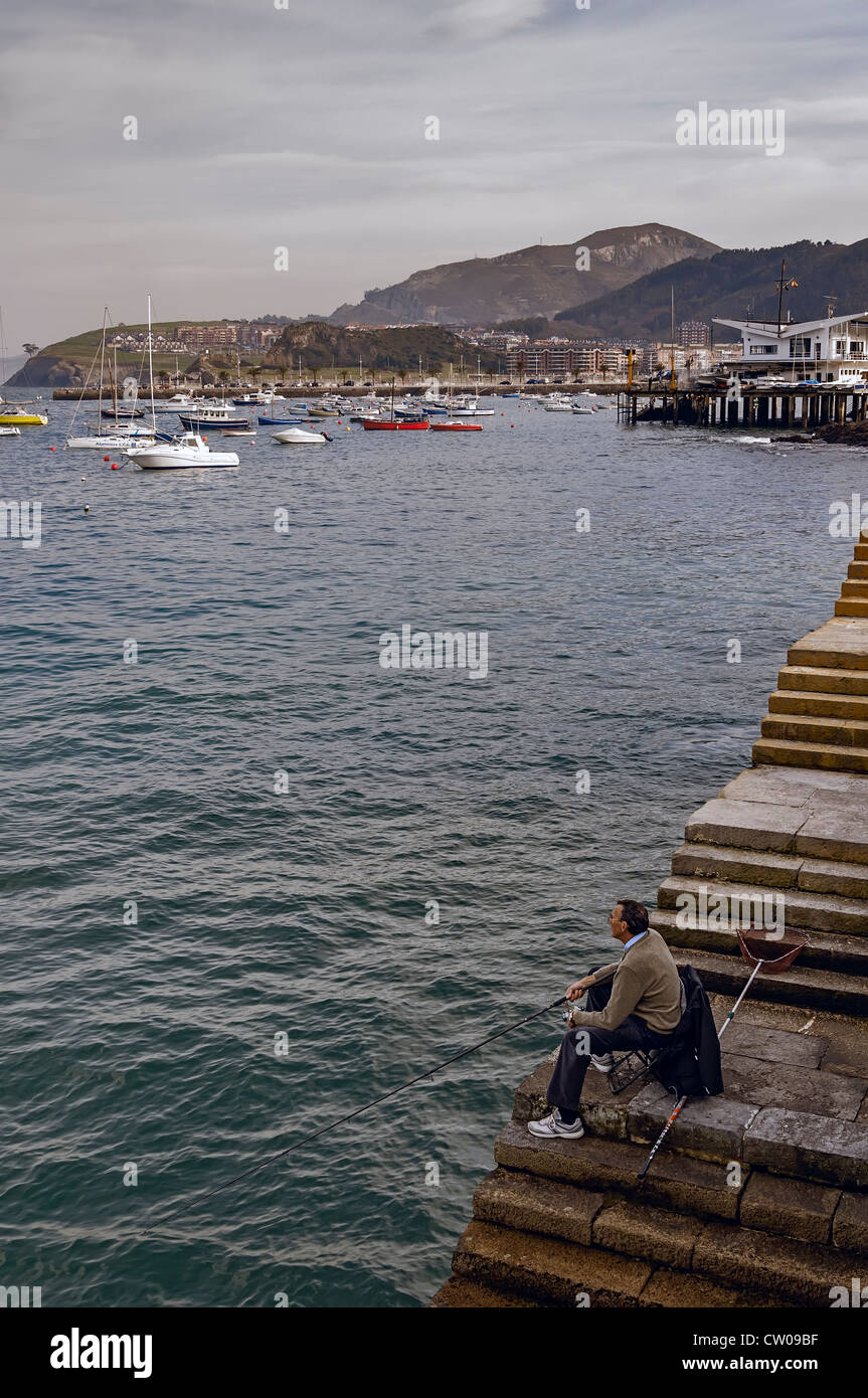 fishing man sitting on the stairs of the promenade of the village of ...