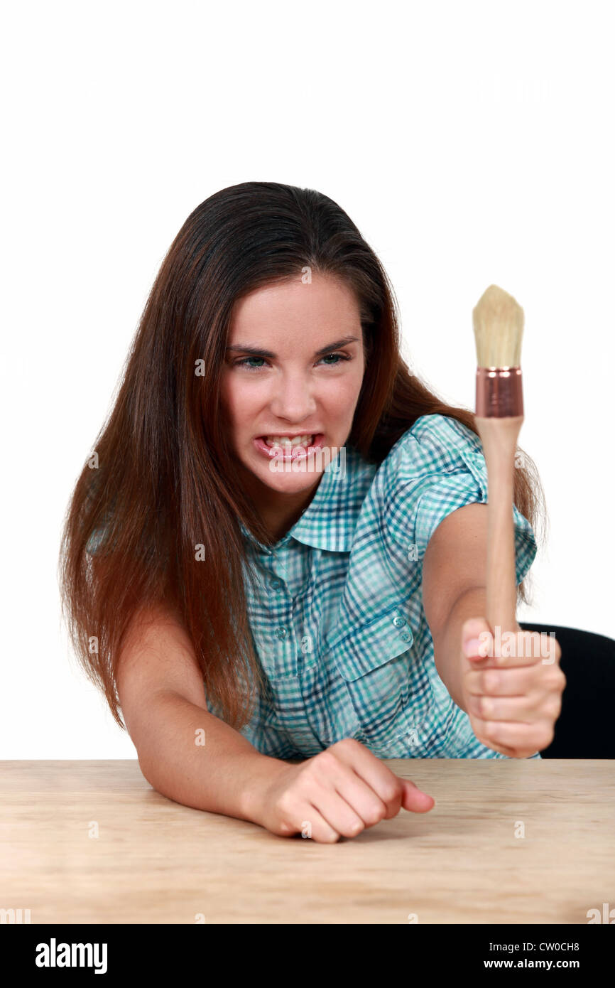 Brown-haired woman baring her teeth and holding a paintbrush Stock ...