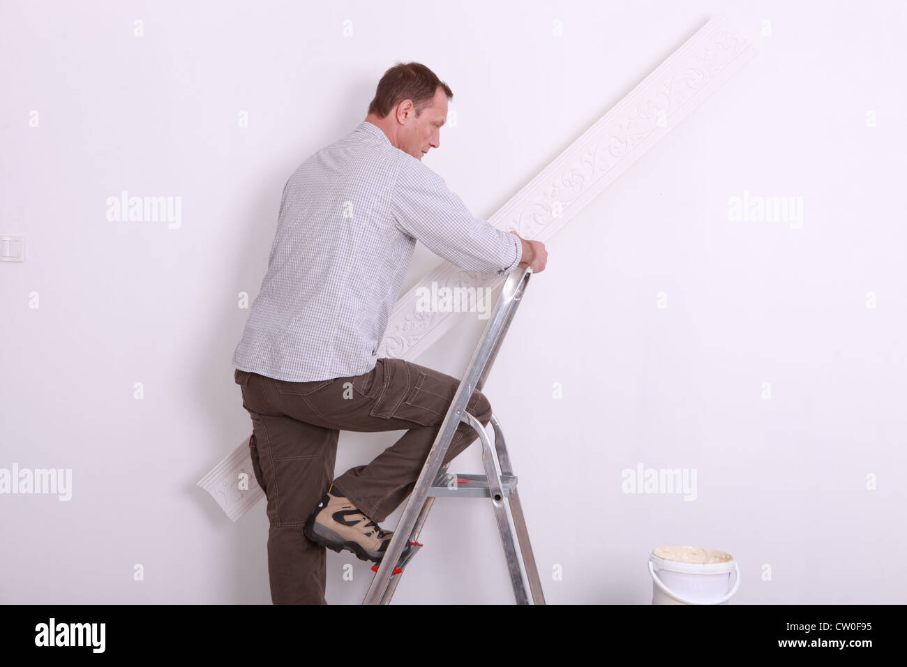 Man climbing ladder holding wallpaper Stock Photo - Alamy