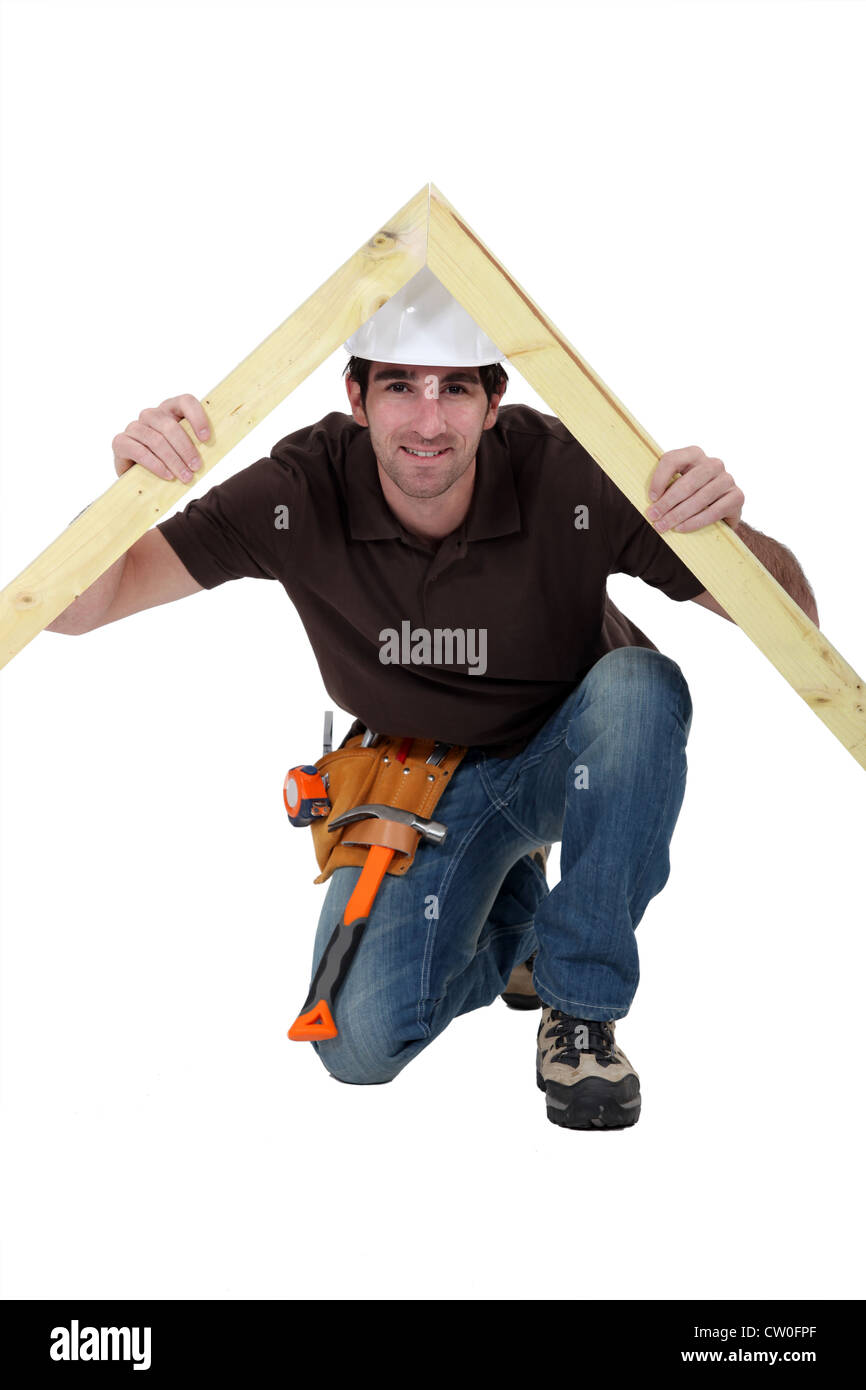 Smiling carpenter holding timber frame Stock Photo - Alamy