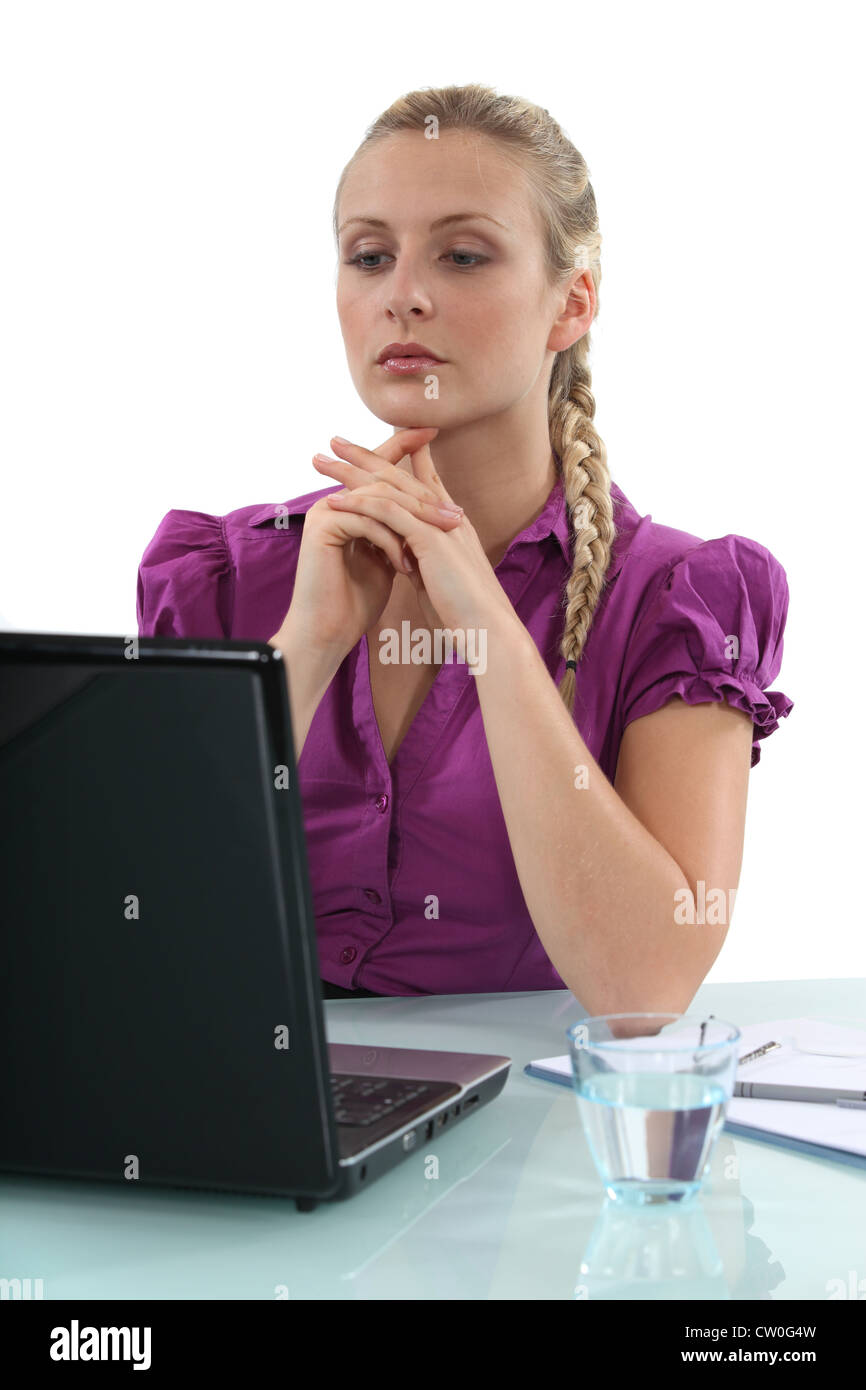 Woman sat at desk with glass of water and laptop Stock Photo - Alamy