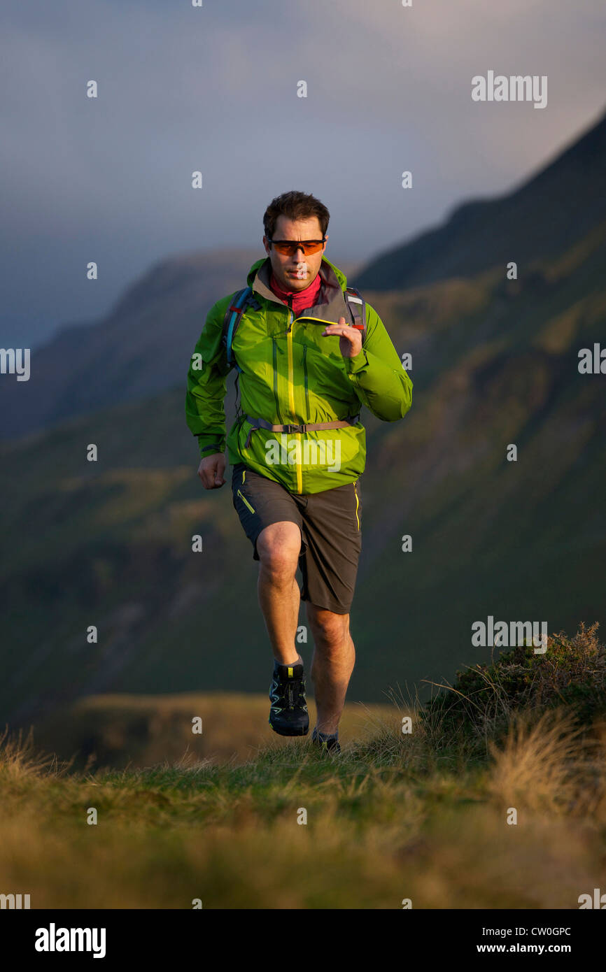 Hiker running in grassy field Stock Photo - Alamy